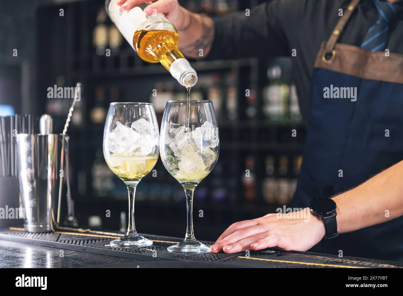 Skilled bartender pours ingredients into glasses at a modern bar, demonstrating cocktail making ...