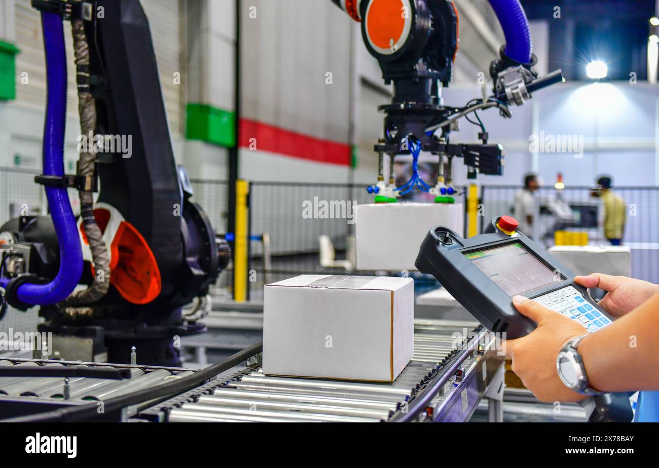 Manager check and control automation robot arms holding a white box and ...