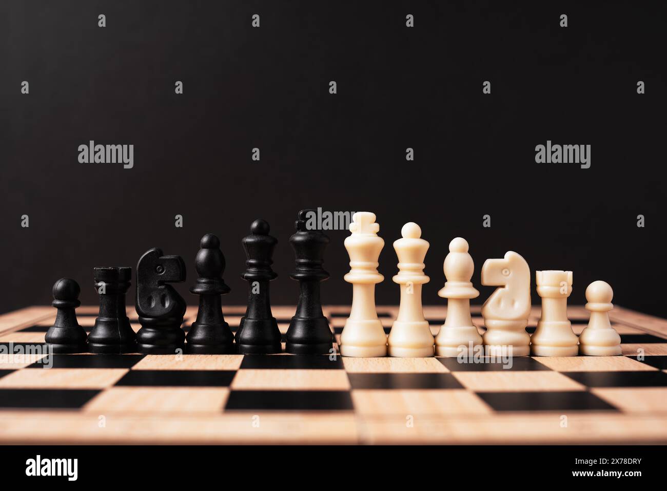 Rows of white and black chess pieces on black background Stock Photo ...