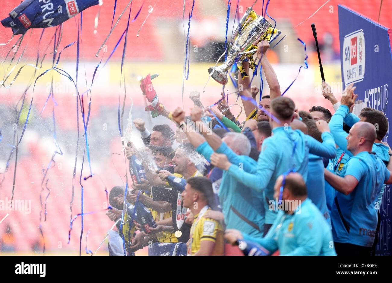 Oxford United's Elliott Moore lifts the trophy on the pitch after the ...