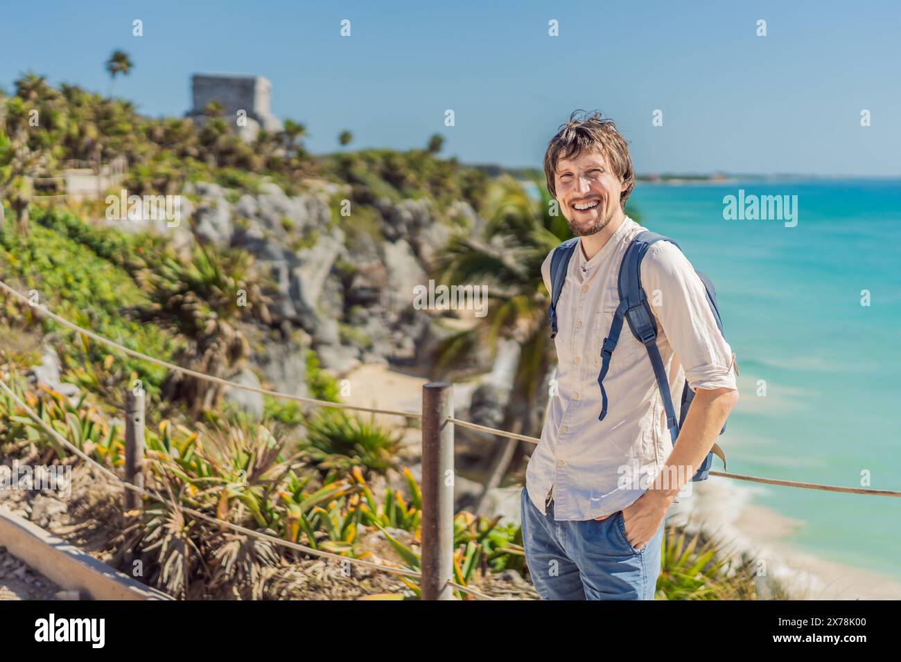 Man tourist enjoying the view Pre-Columbian Mayan walled city of Tulum ...