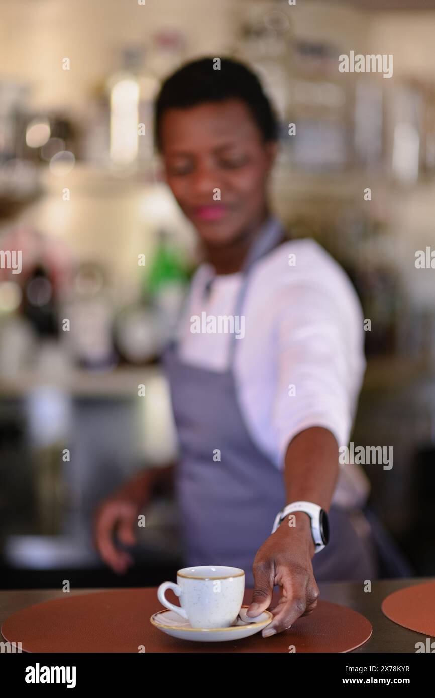Blurred background with a focused barista handing over a freshly brewed ...