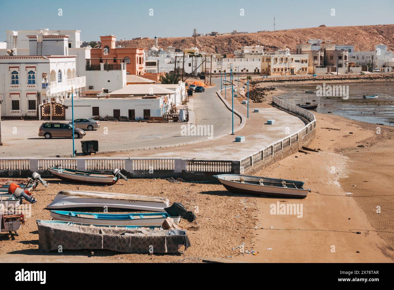 Small fishing boats on the sandy shore in Sur, Oman, with a curved ...