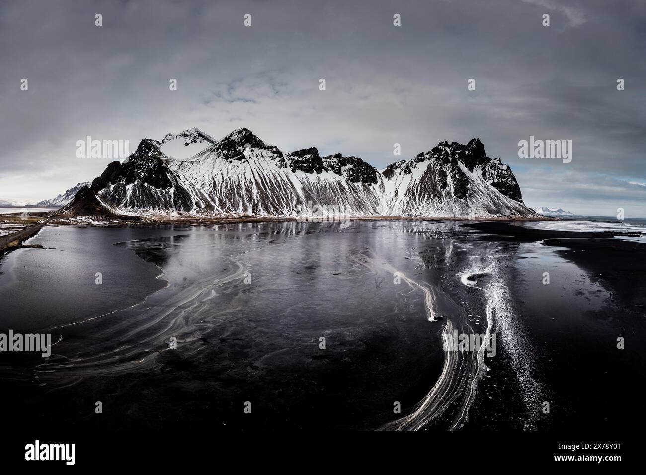 Snow-covered Vestrahorn mountains reflecting in icy waters at Stokksnes ...