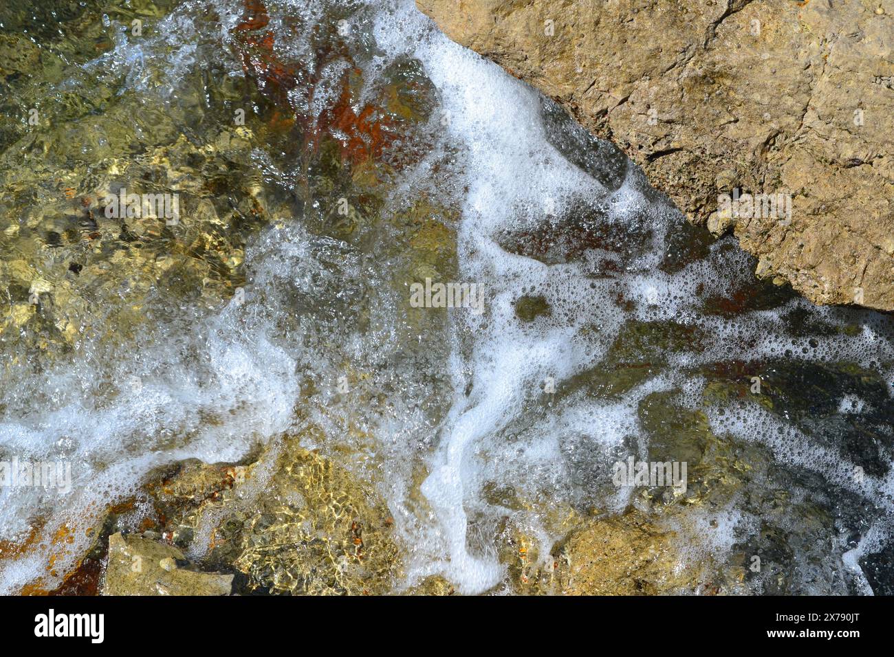 Barnacles cover the rocks while waves surge over them at Ponce Inlet ...