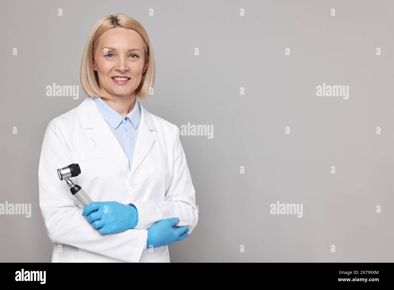Happy dermatologist with dermatoscope on grey background, space for ...
