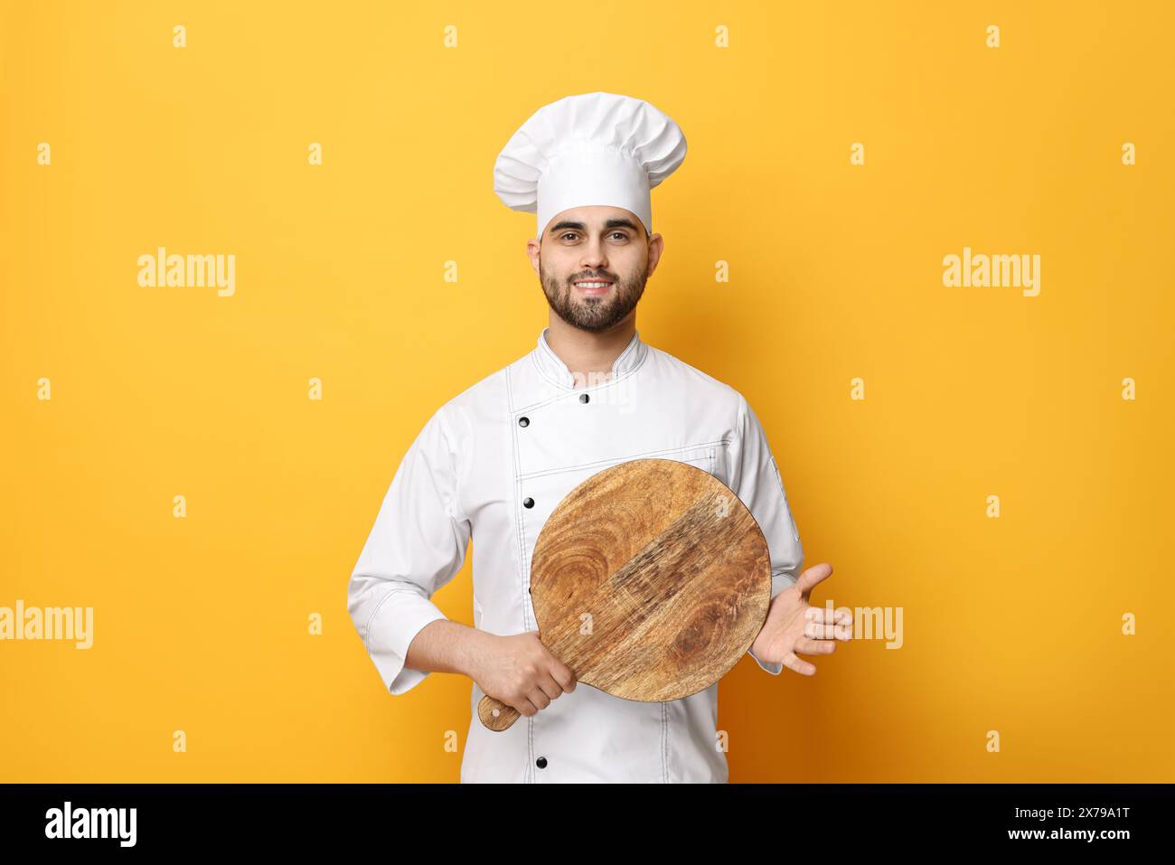 Professional chef with serving board on yellow background Stock Photo ...