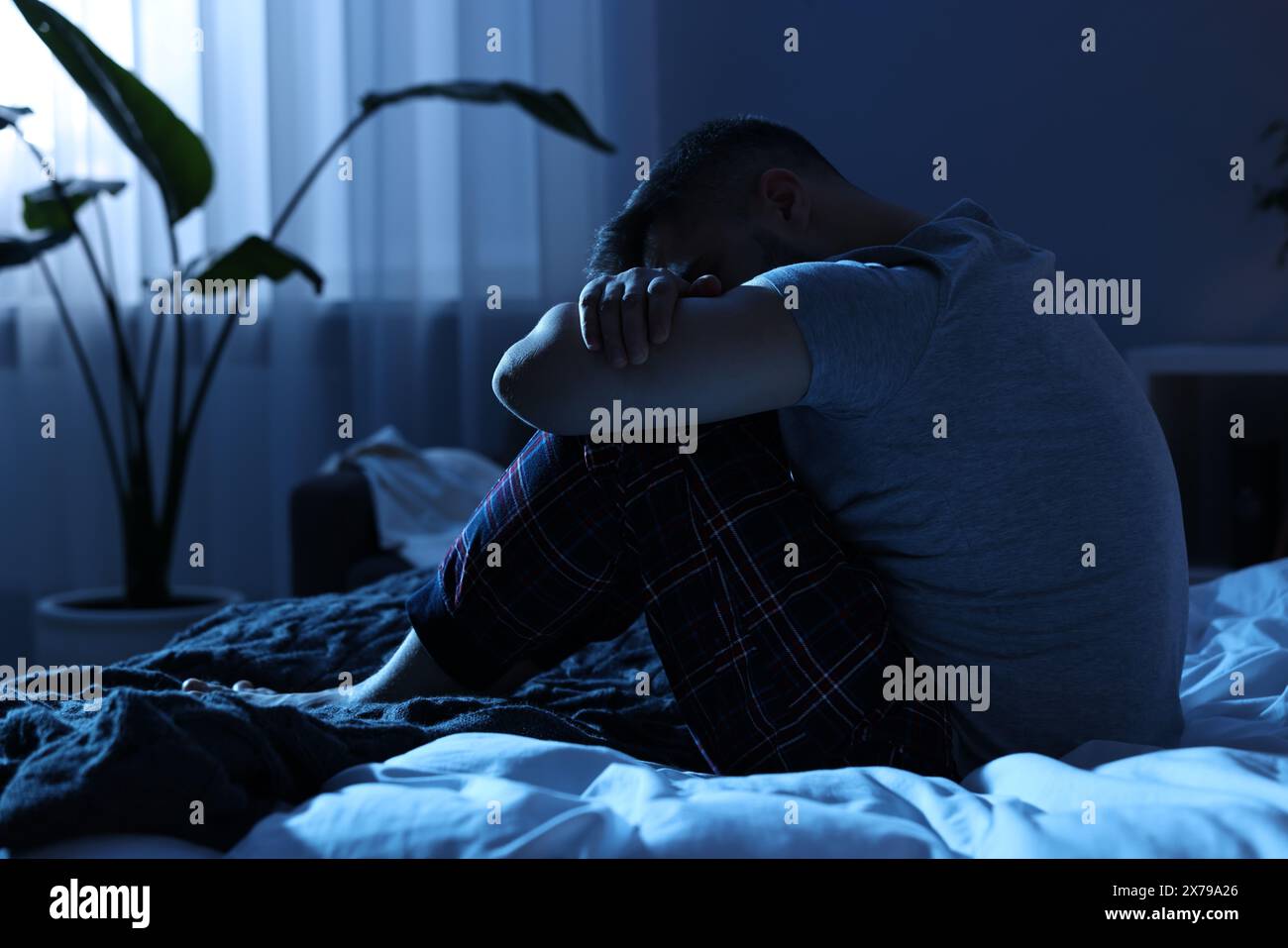 Tired man sitting on bed at night Stock Photo - Alamy