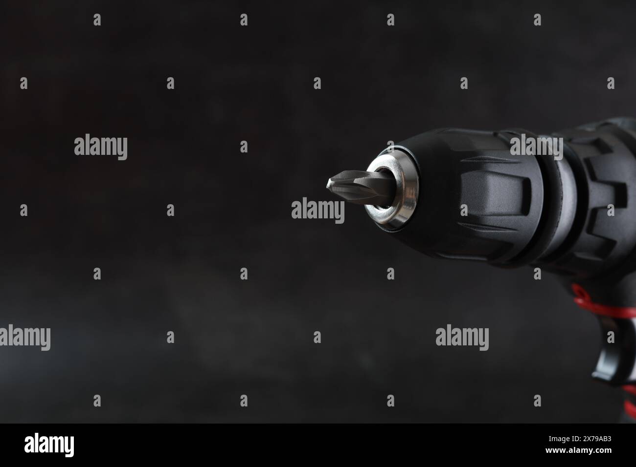 Modern electric screwdriver on dark grey background, closeup. Space for ...