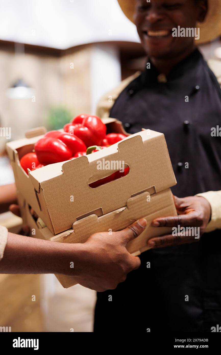 A smiling black man in a modern store offers fresh local produce ...