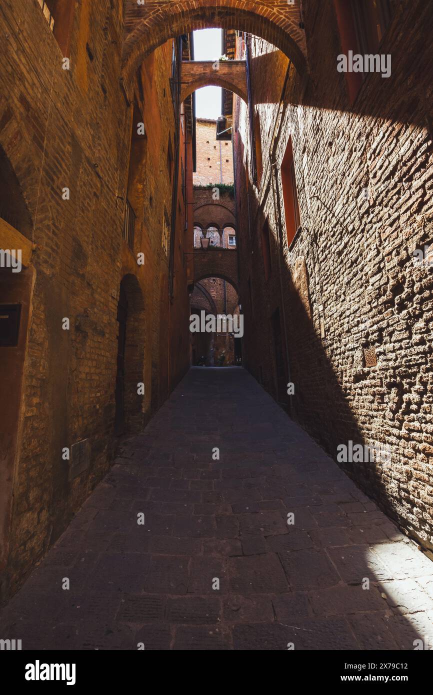 A narrow alley in the historic medieval old town of Siena in Tuscany ...