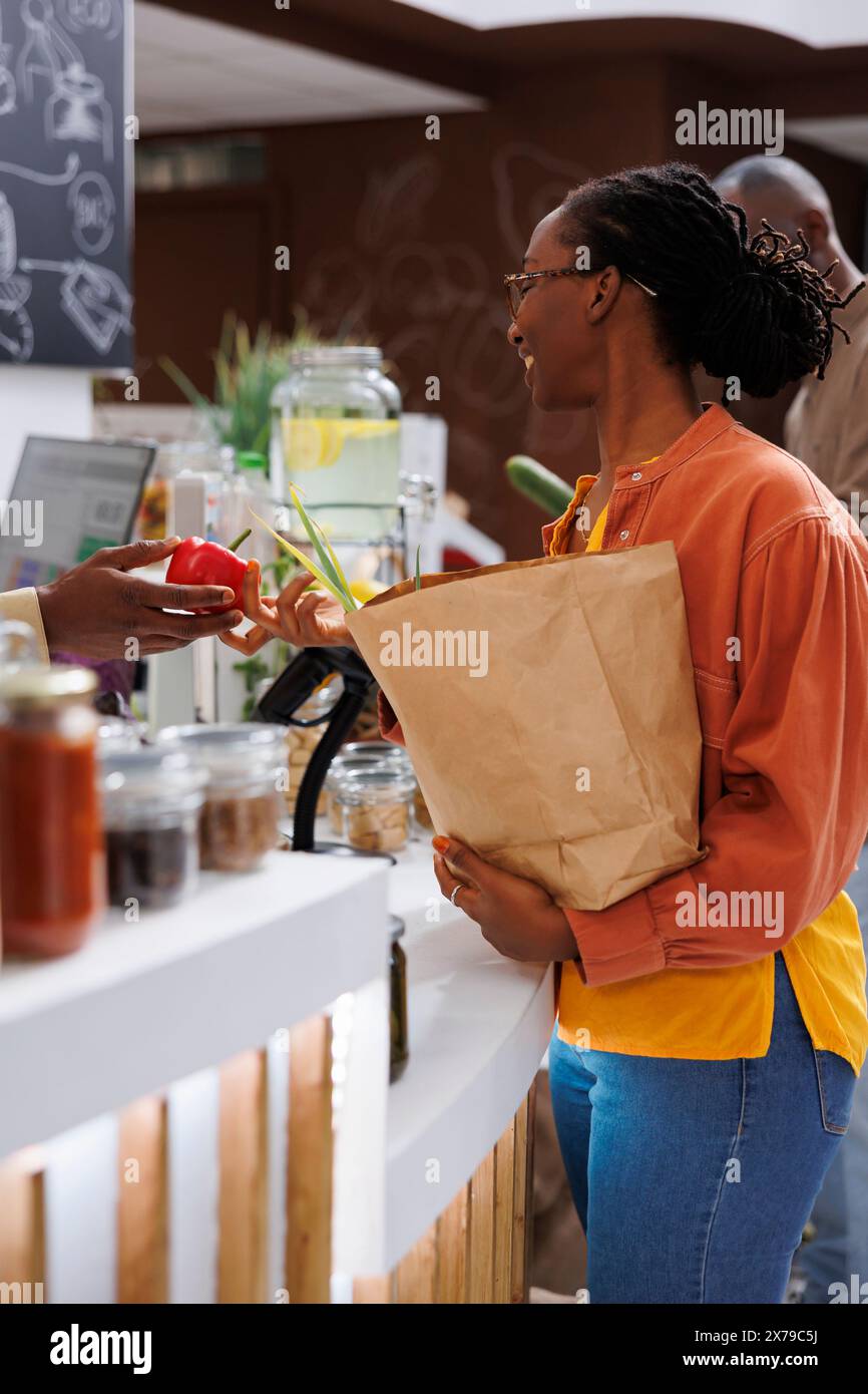 Image of black woman with a grocery bag handing over red pepper to the ...