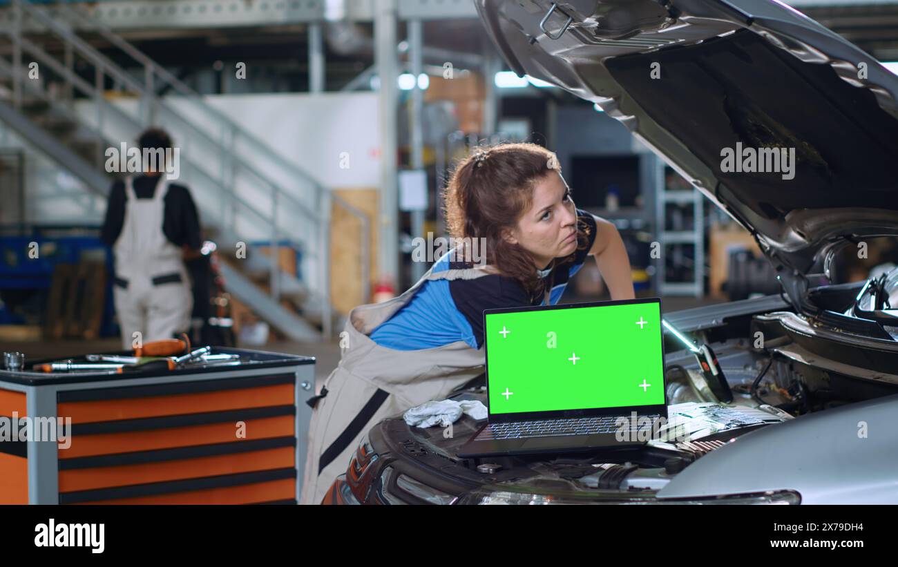 Chroma key laptop in garage facility sitting on malfunctioning car ...