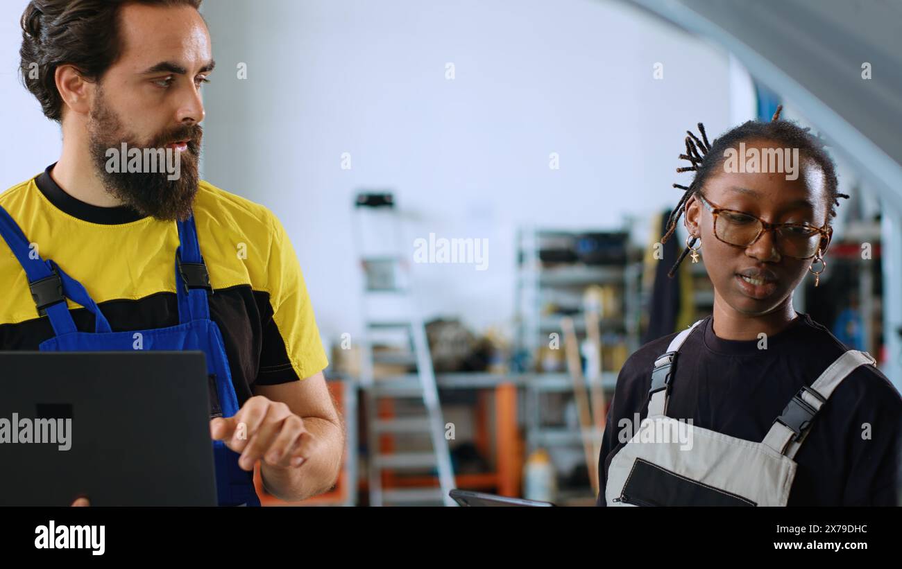 Engineer and colleague doing car maintenance in repair shop using ...