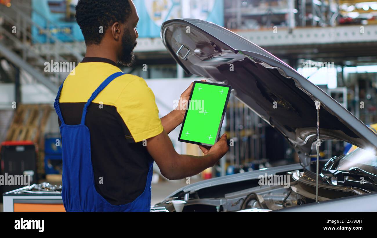 Trained repairman using green screen tablet in car service to order new ...