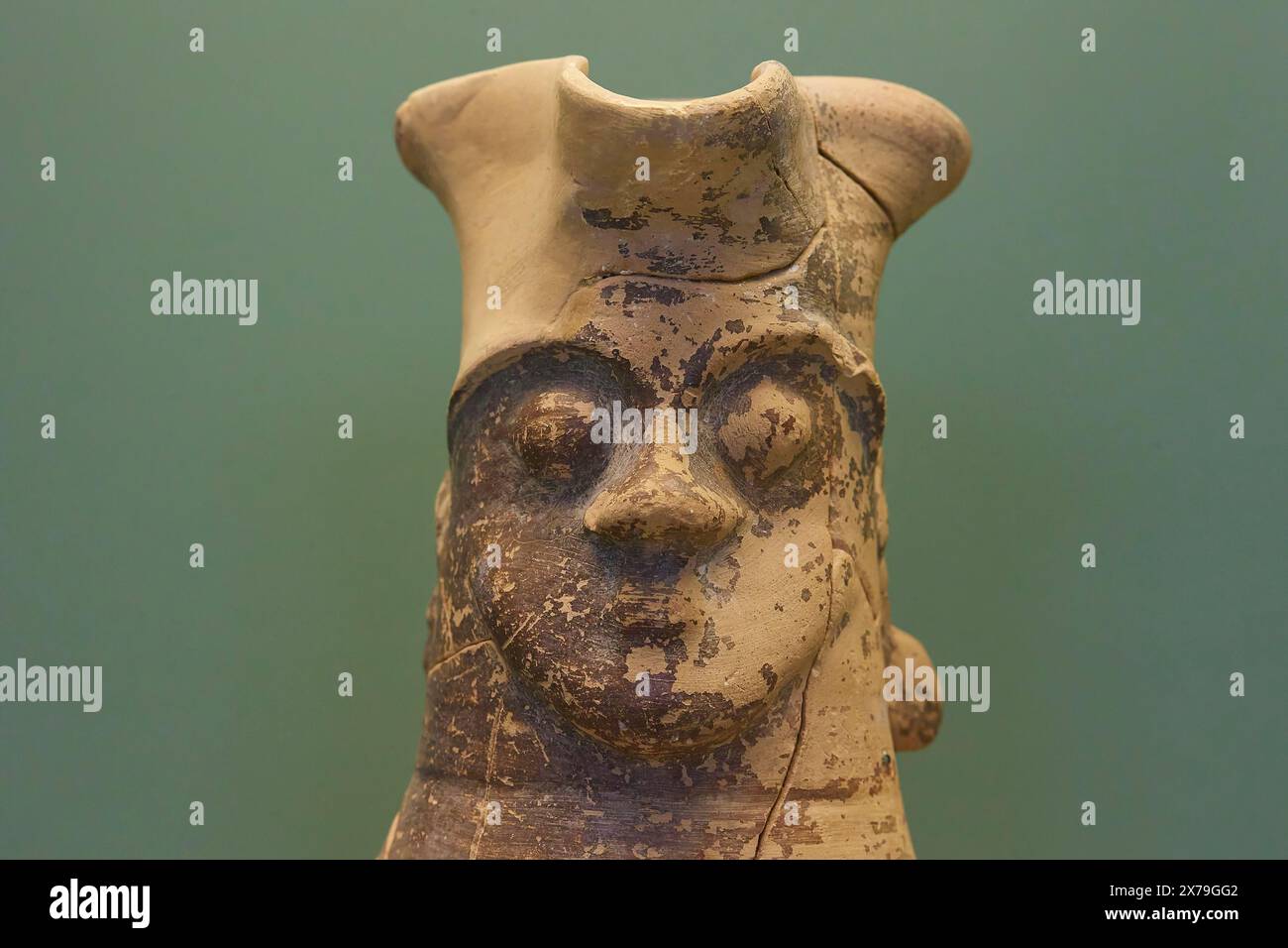 Large antique sculpture of a face with faded colours against a green ...