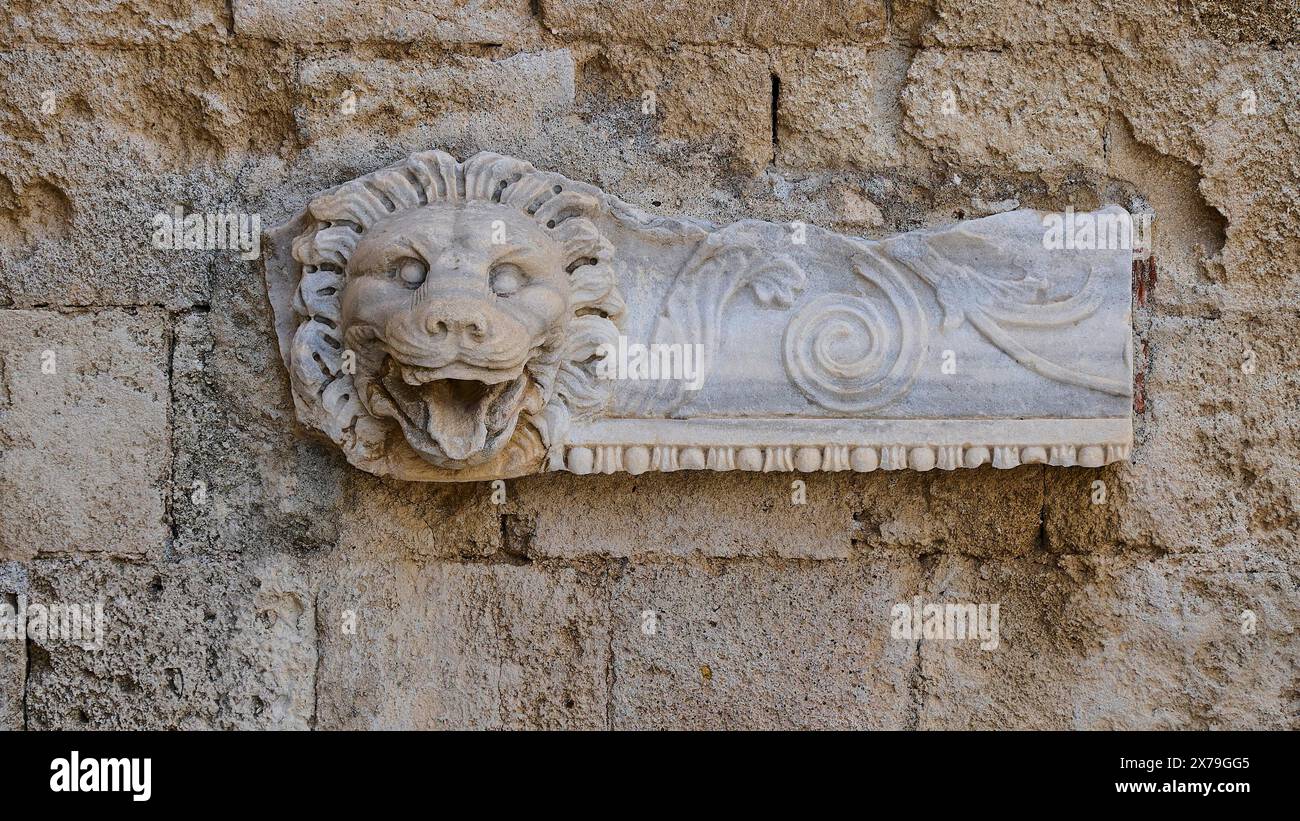 Ancient stone relief of a lion's head, carved into a wall, rich in ...