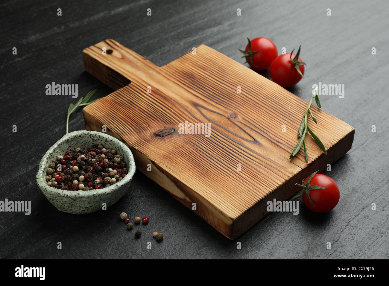 Wooden cutting board, fresh tomatoes and different spices on grey ...