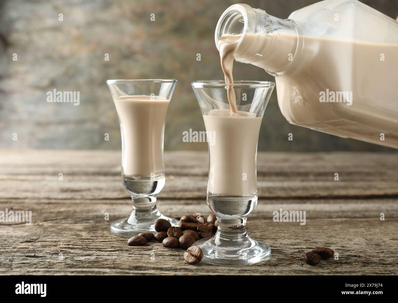 Pouring coffee cream liqueur into glass at wooden table, closeup Stock ...