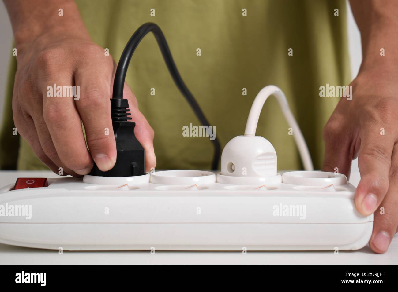 A man cuts off the electric current at a white electrical socket to ...