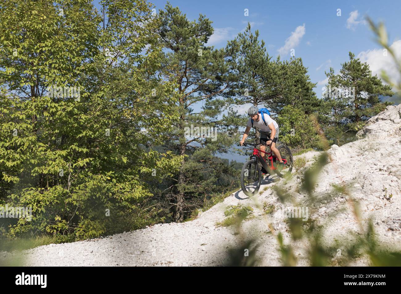Male electric mountain bike rider going downhill and braking on a hilly ...