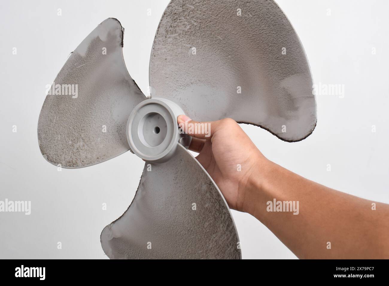 Hands holding dusty fan blades, dust on the fan has an impact on the ...