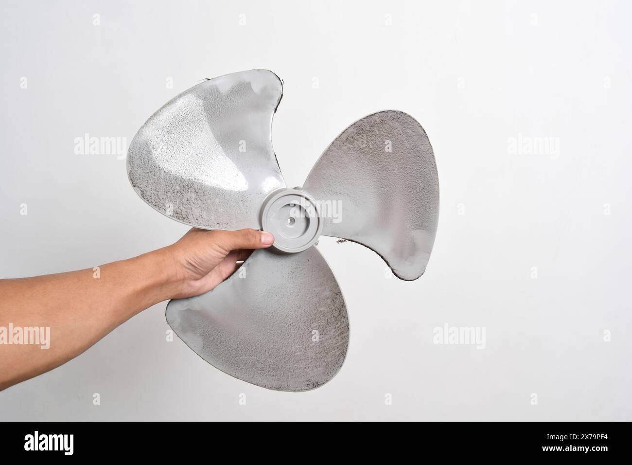 Hands holding dusty fan blades, dust on the fan has an impact on the ...