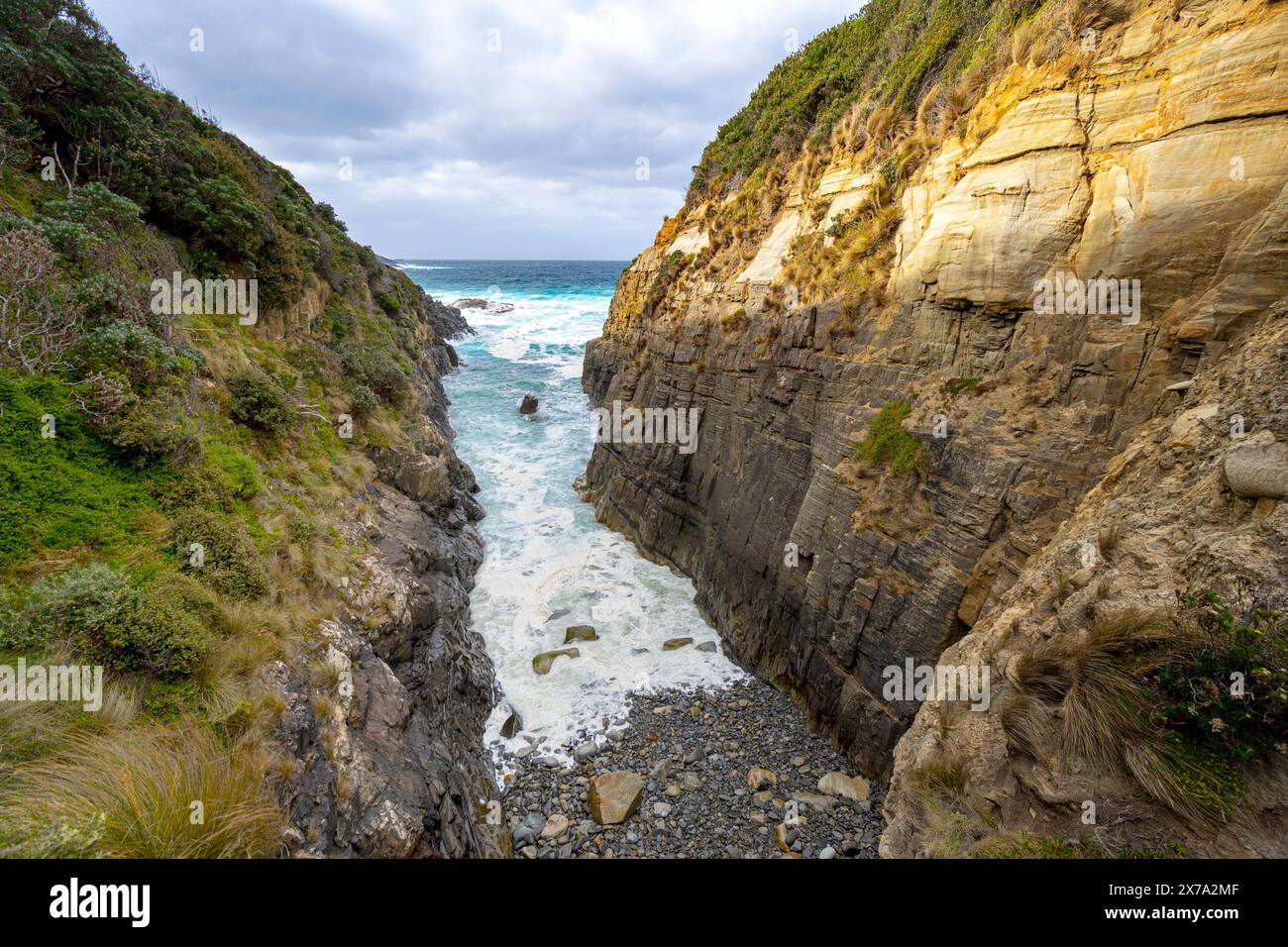 Narrow chasm in sea cliffs eroded by powerful ocean swells, Maingon Bay ...