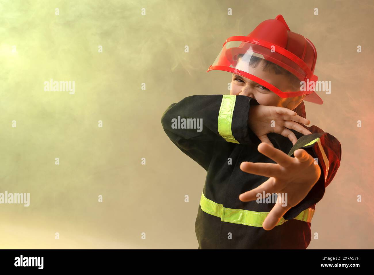 Cute little firefighter in smoke on grey background Stock Photo - Alamy