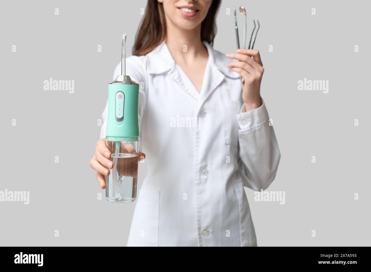 Female dentist with oral irrigator and tools on grey background Stock ...