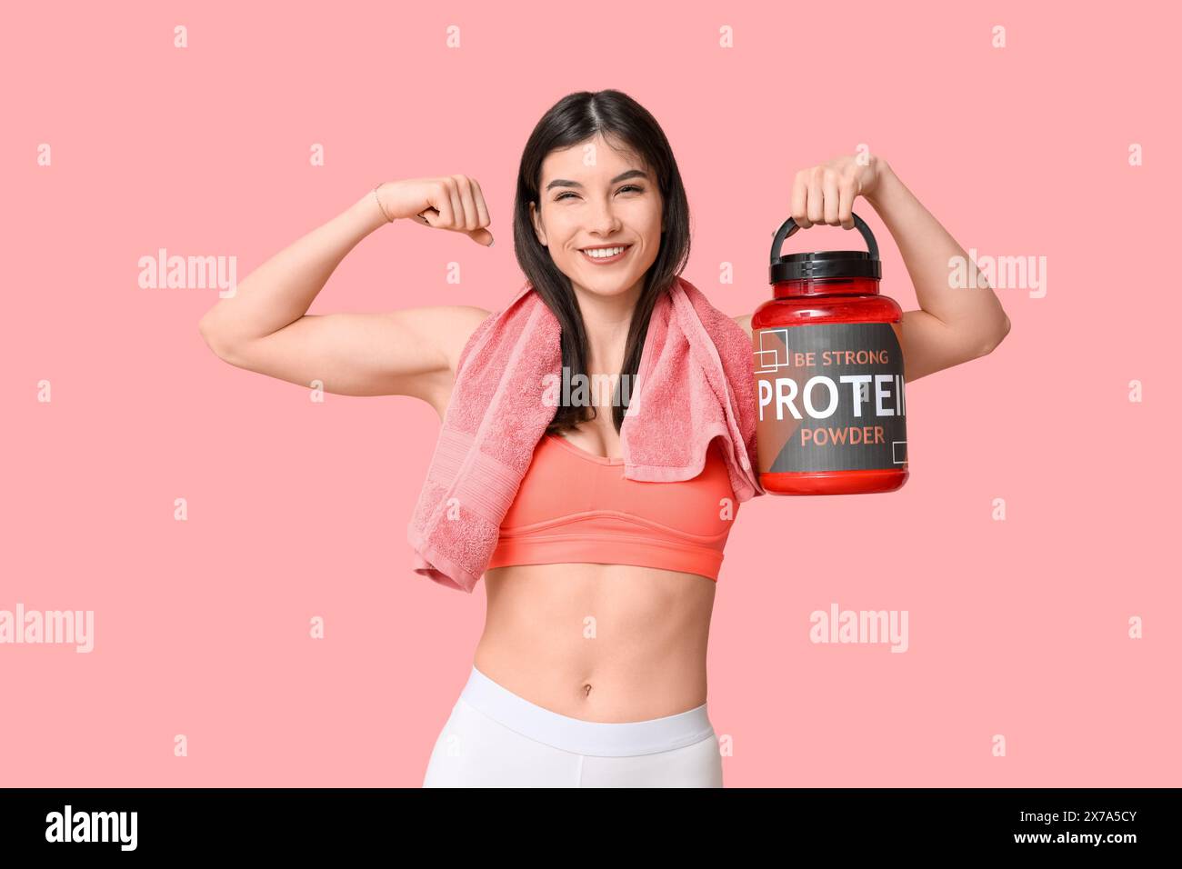 Sporty young woman with bottle of protein powder showing muscles on ...
