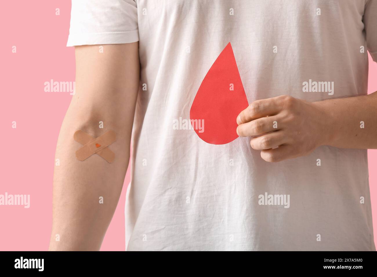 Blood donor with applied medical patches and paper blood drop on pink ...