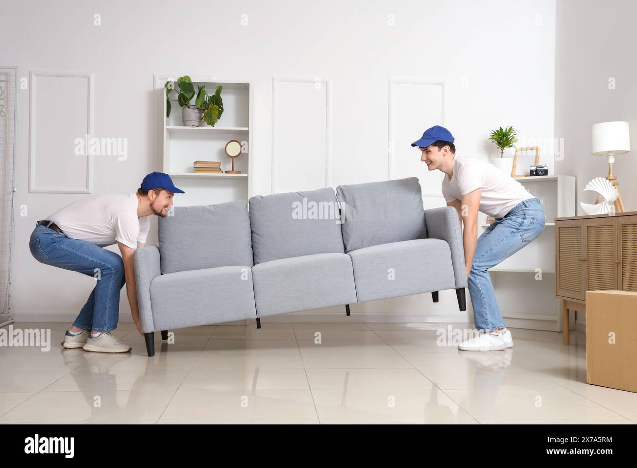 Loaders carrying sofa in room Stock Photo - Alamy
