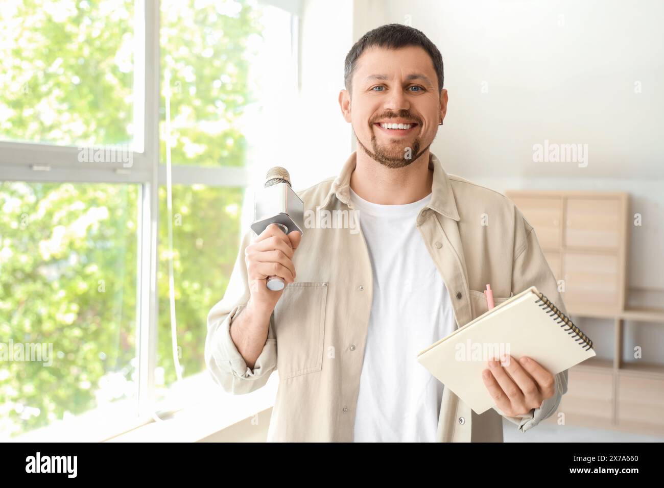 Male reporter with microphone and notebook in studio Stock Photo - Alamy