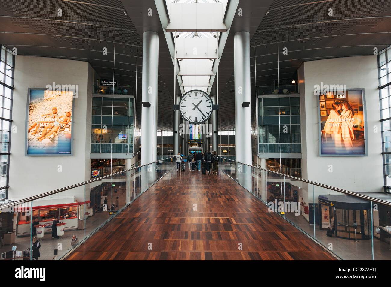 a large analog clock and advertising billboards inside the entrance to ...