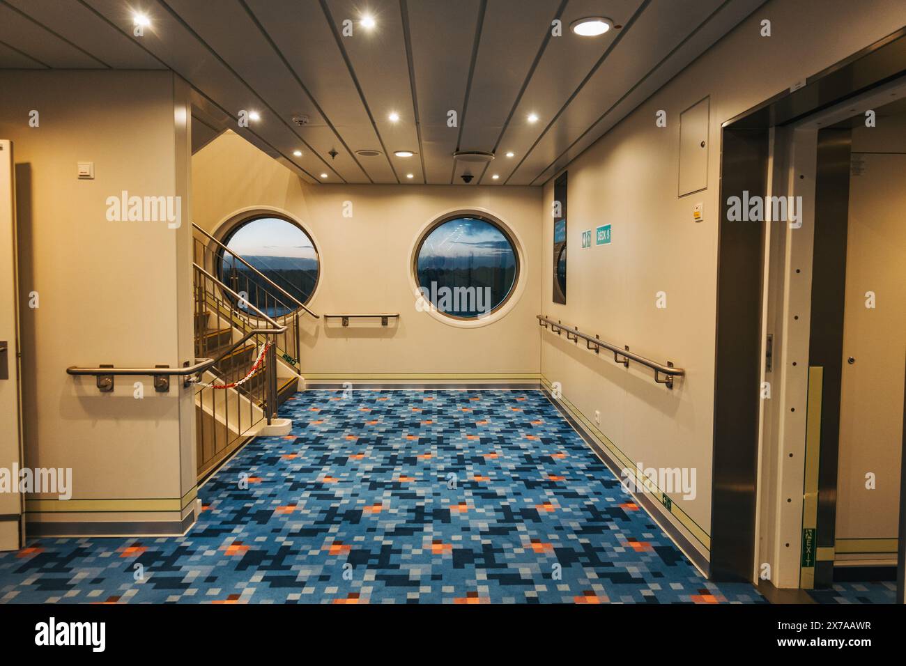 the white walls and blue carpet of the passenger cabin hallway of a ...