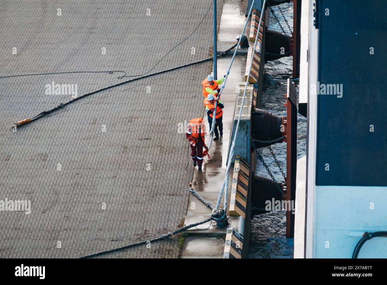 Port workers in Klaipėda, Lithuania, work to moor a ferry using ropes ...