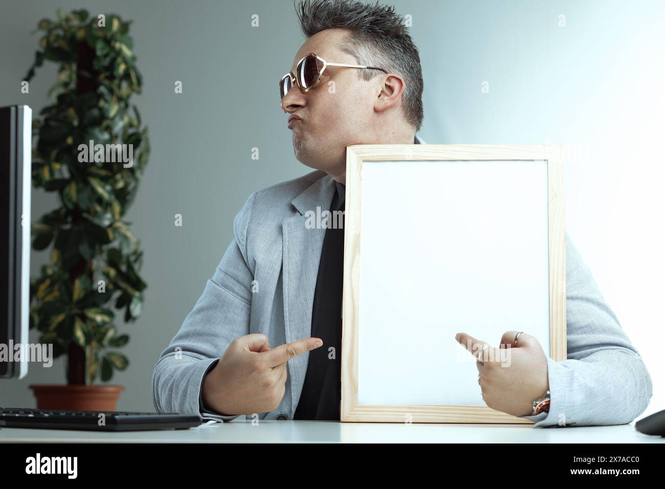 Confident man with spiky gray hair and sunglasses points at a blank ...