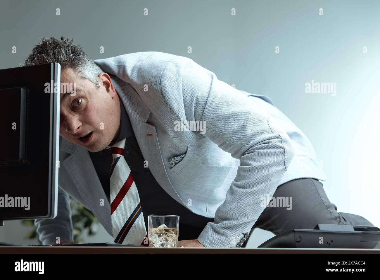 man, dressed in a light suit and striped tie, appears startled while ...