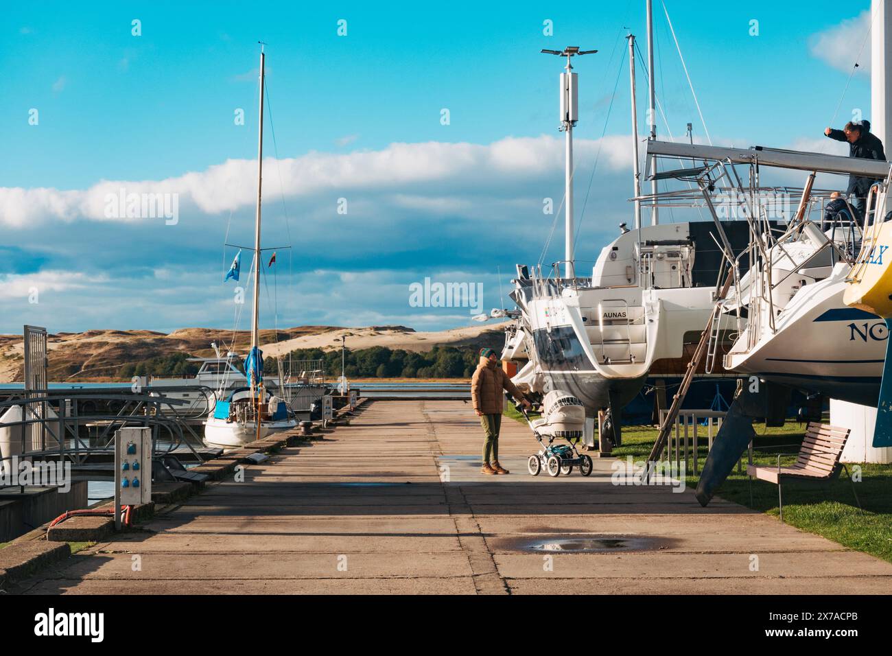 A family tend to their boat stored on shore in a marina in Nida ...