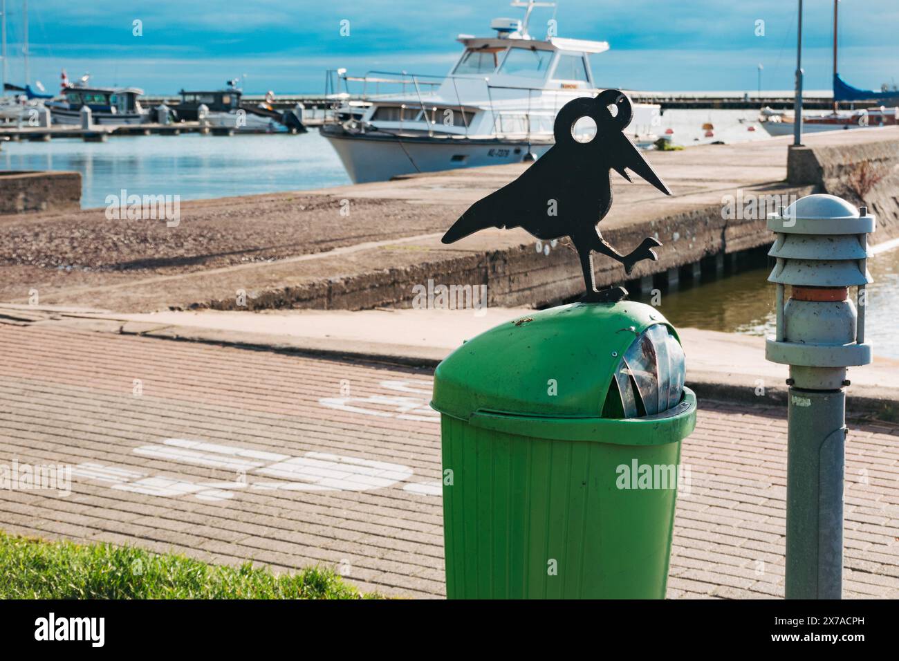 a metal cut out of a crow on top of a rubbish bin in the seaside town ...