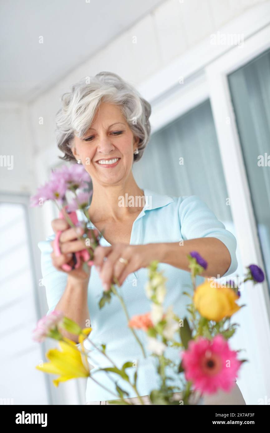 Senior, woman and happy to arrange flowers in home, vase and creativity ...