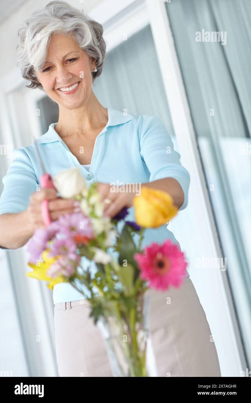 Senior, woman and happy to arrange flowers in home, vase and creativity ...
