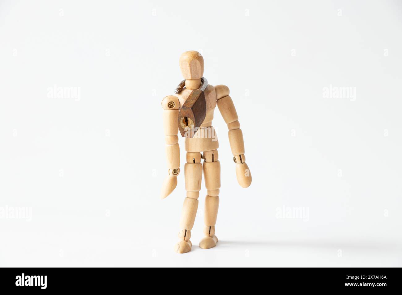 Wooden doll man with a padlock on his neck stands on a white background ...
