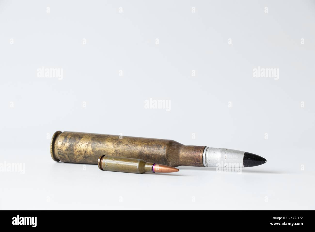 Two bullets, large and small, lie on a white background close-up Stock ...