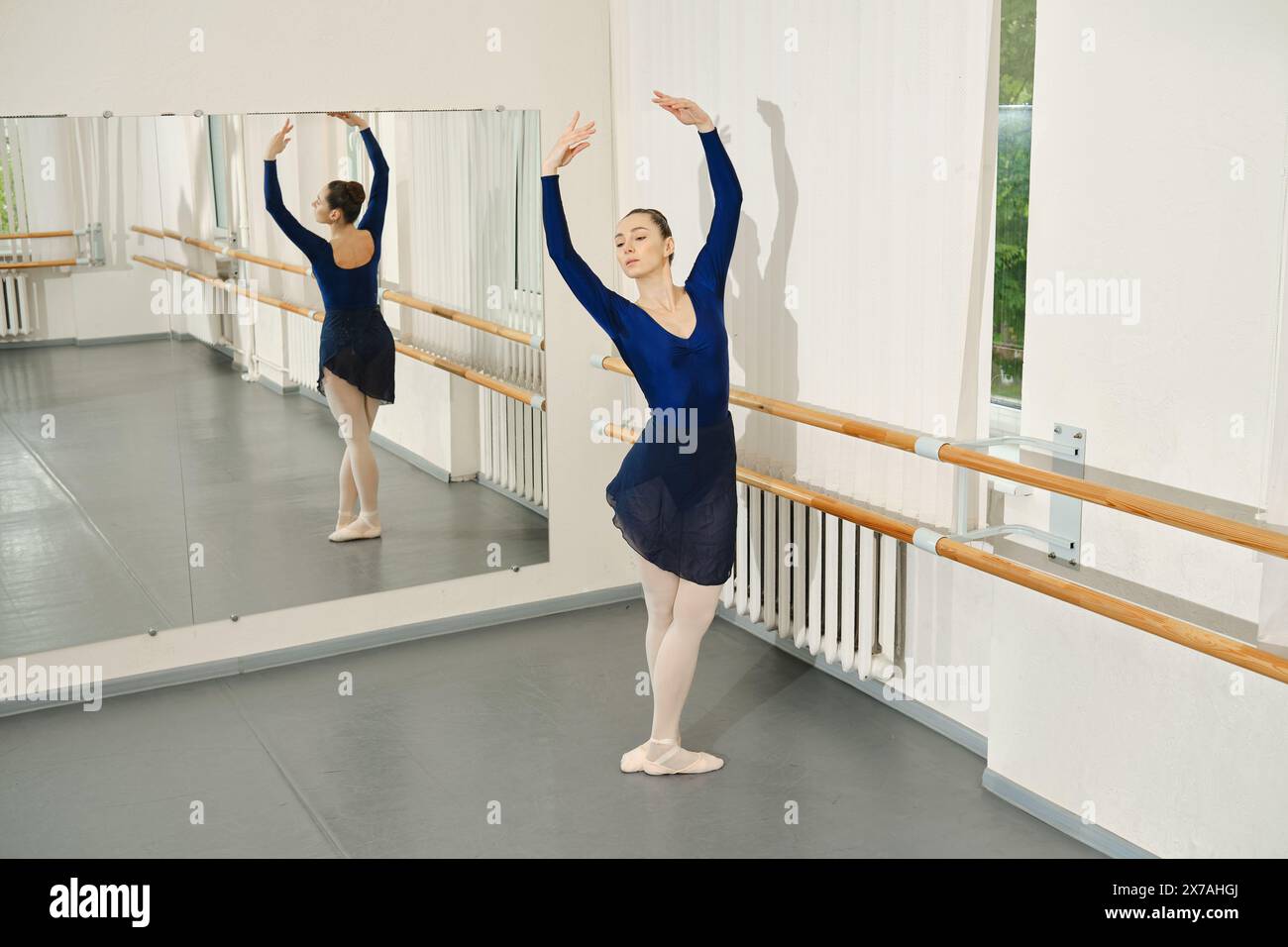 Ballerina stands in third position with arms raised in choreographic ...