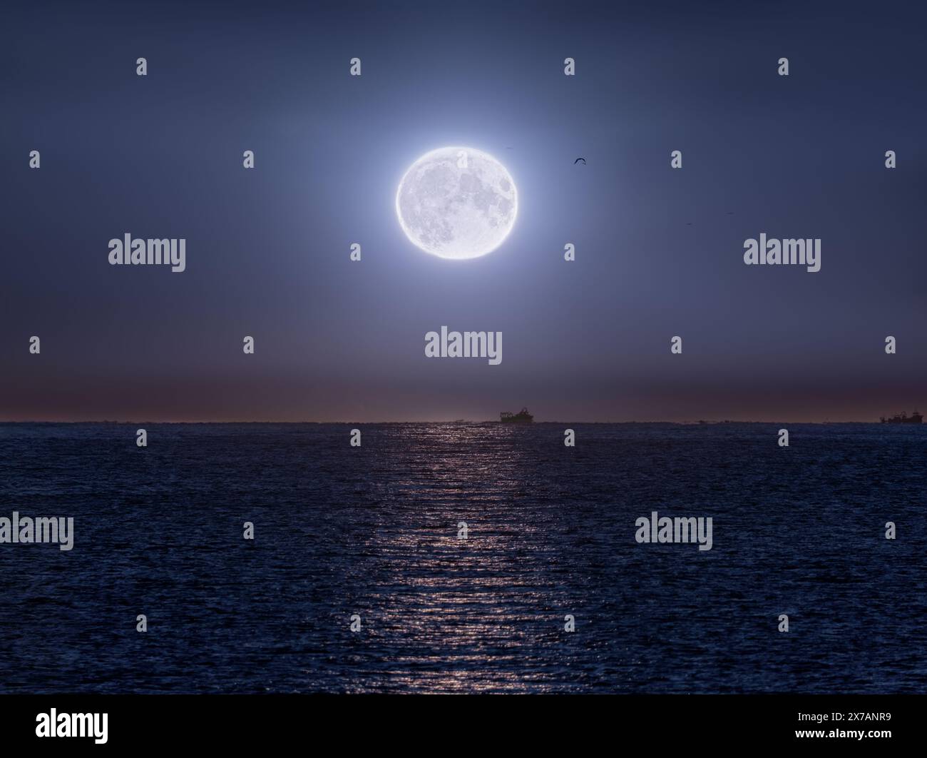 Fishing boat silhouette illuminated by the light of the full moon in a ...