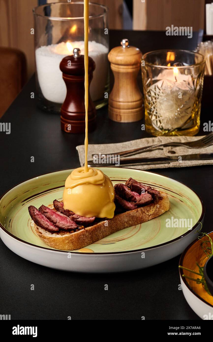 Beef steak slices on toasted bread with poached egg and sauce Stock ...