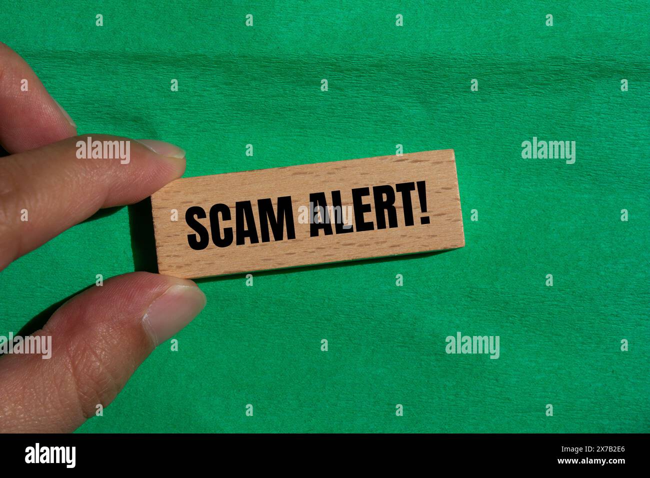 Scam alert words written on wooden block with green background ...