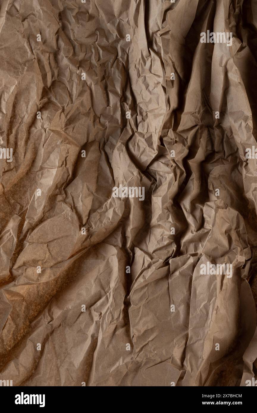 Brown wrinkled paper sheet with deep fold and shades close up view ...